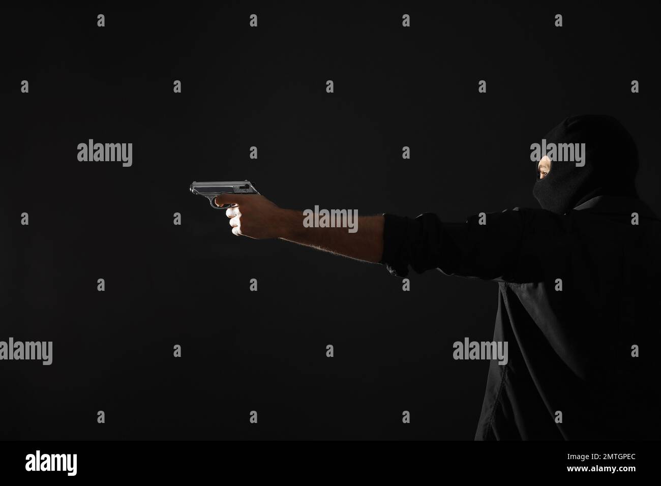 Professional killer with gun on black background Stock Photo - Alamy