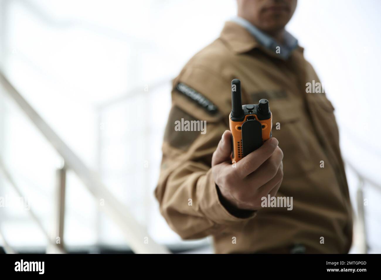 Professional security guard with portable radio set indoors, closeup ...