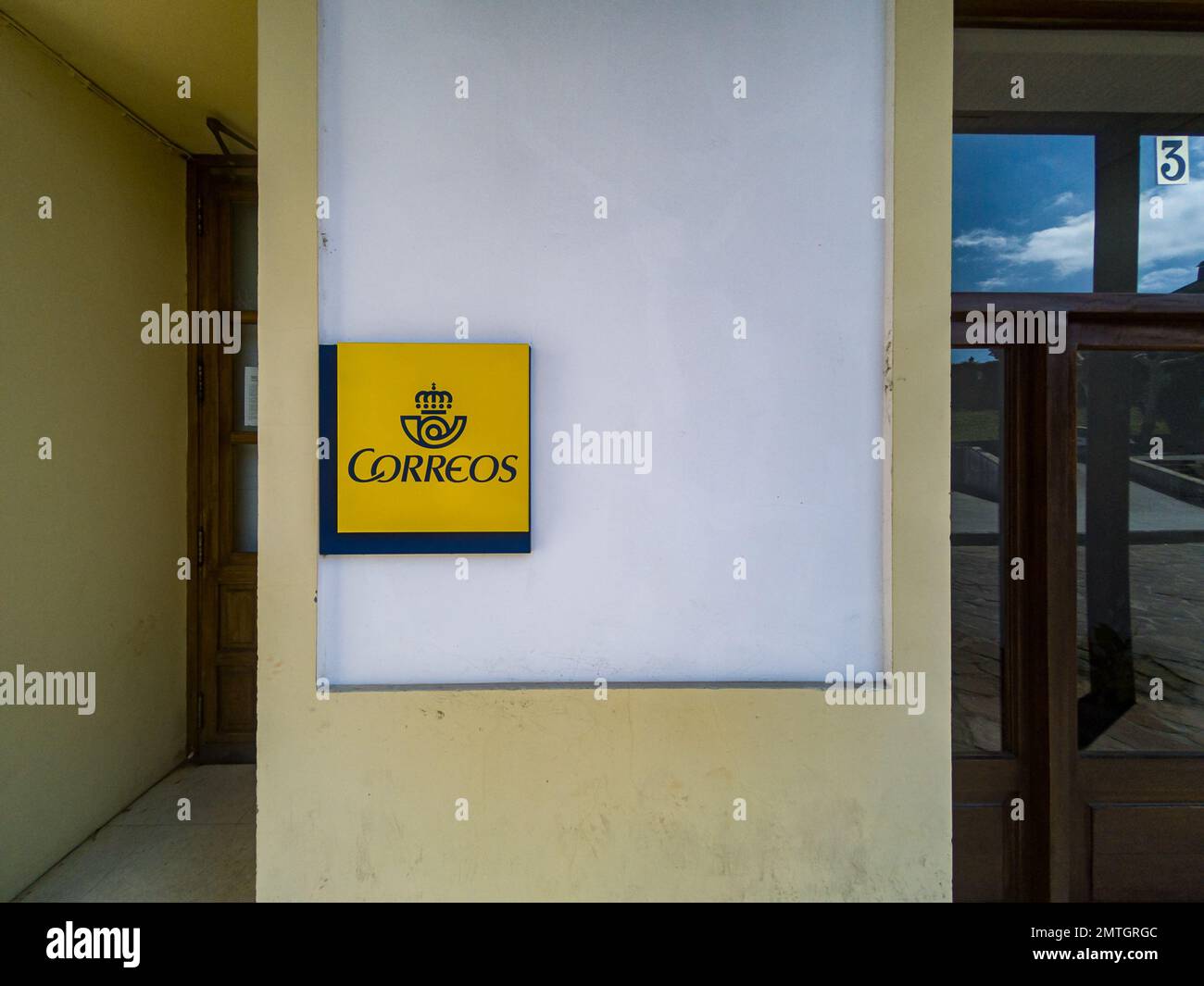 A yellow logo of the Spanish national Correos post company on a wall ...