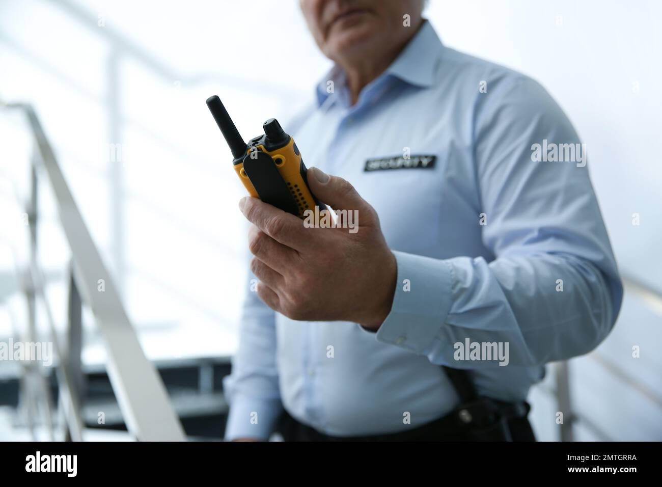 Professional security guard with portable radio set on stairs, closeup ...