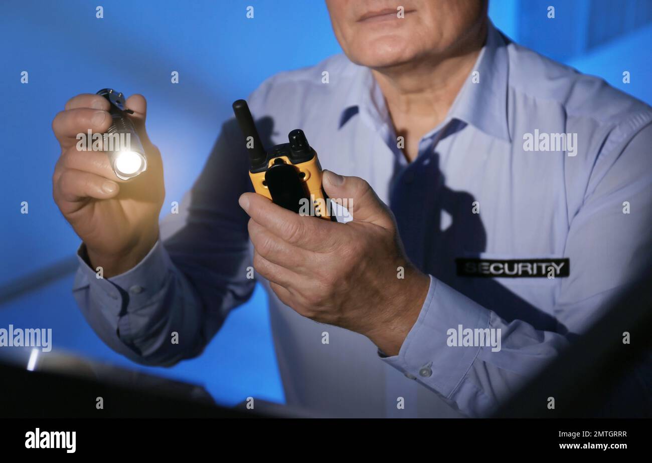 Professional security guard with portable radio set and flashlight in ...