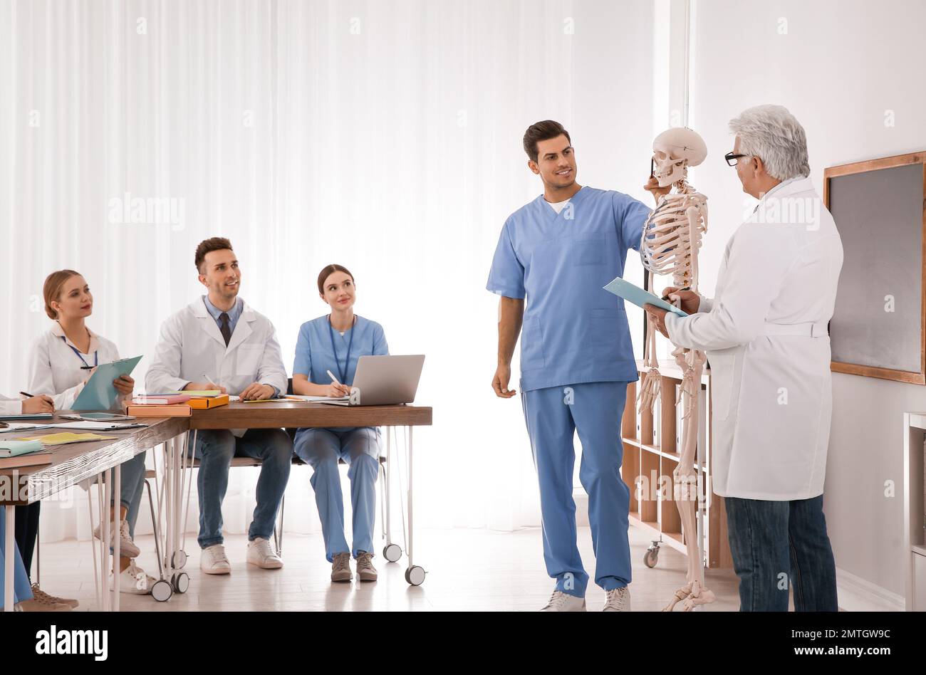 Medical students and professor studying human skeleton anatomy in ...