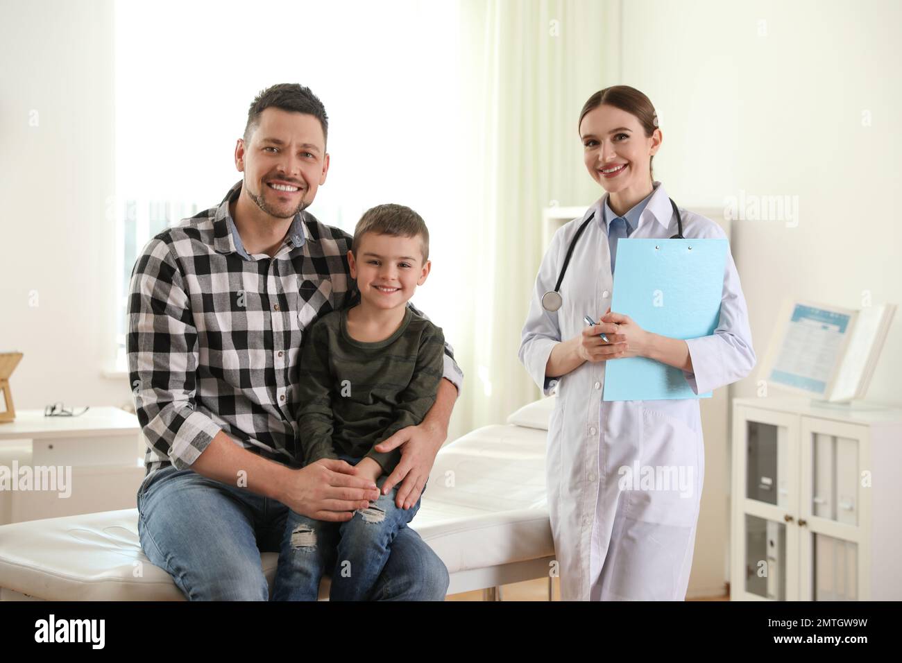 Father and son visiting pediatrician. Doctor working with patient in ...