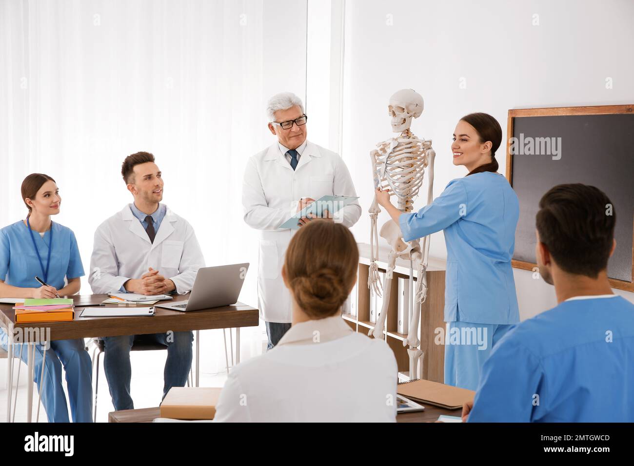 Medical students and professor studying human skeleton anatomy in ...