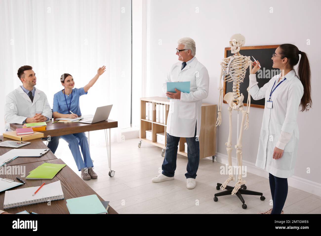 Medical students and professor studying human skeleton anatomy in ...