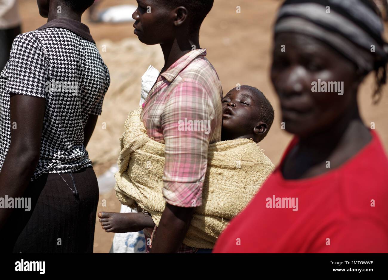 A South Sudanese refugee baby sleeps on his mother's back as she waits ...