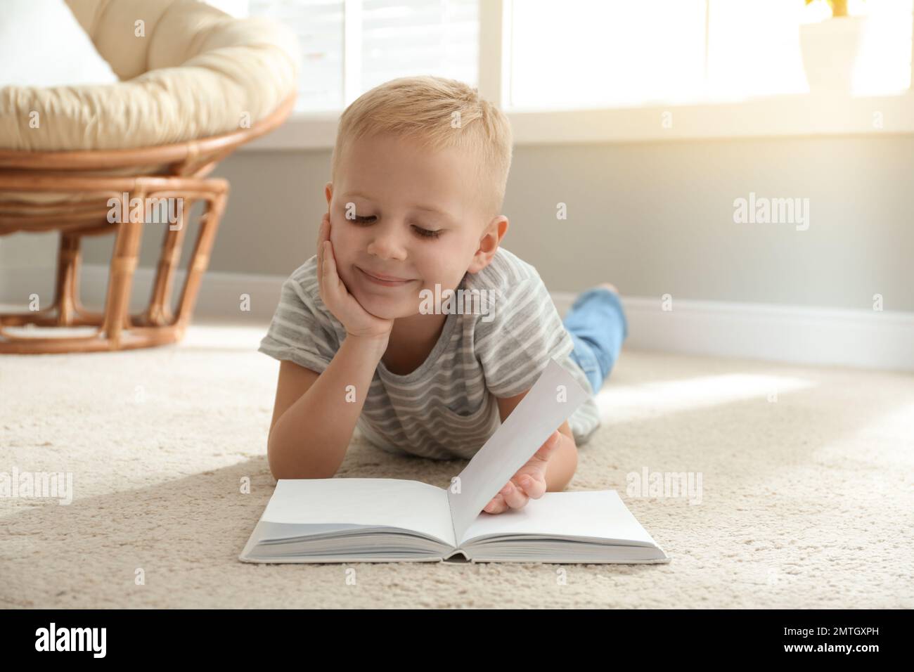 Cute little boy reading book on floor at home Stock Photo - Alamy