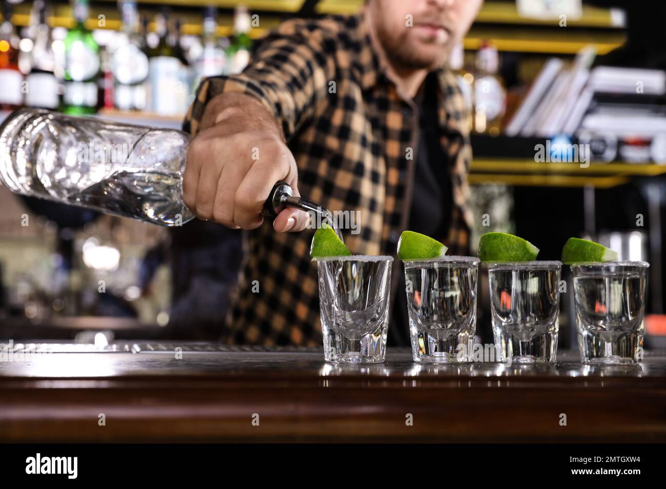 Bartender pouring Mexican Tequila into shot glasses at bar counter, closeup Stock Photo - Alamy