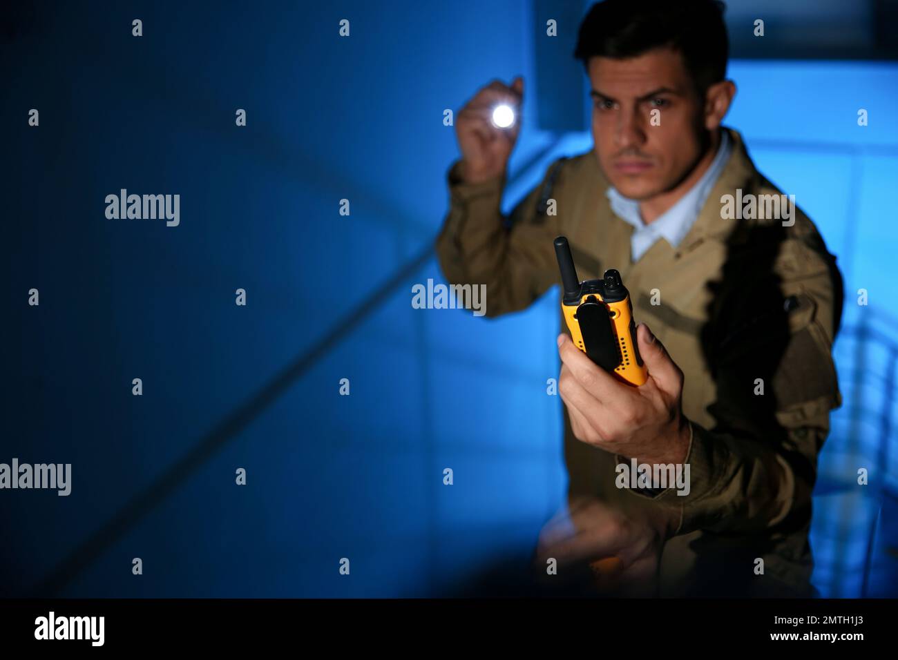 Professional security guard with portable radio set in dark room, focus ...