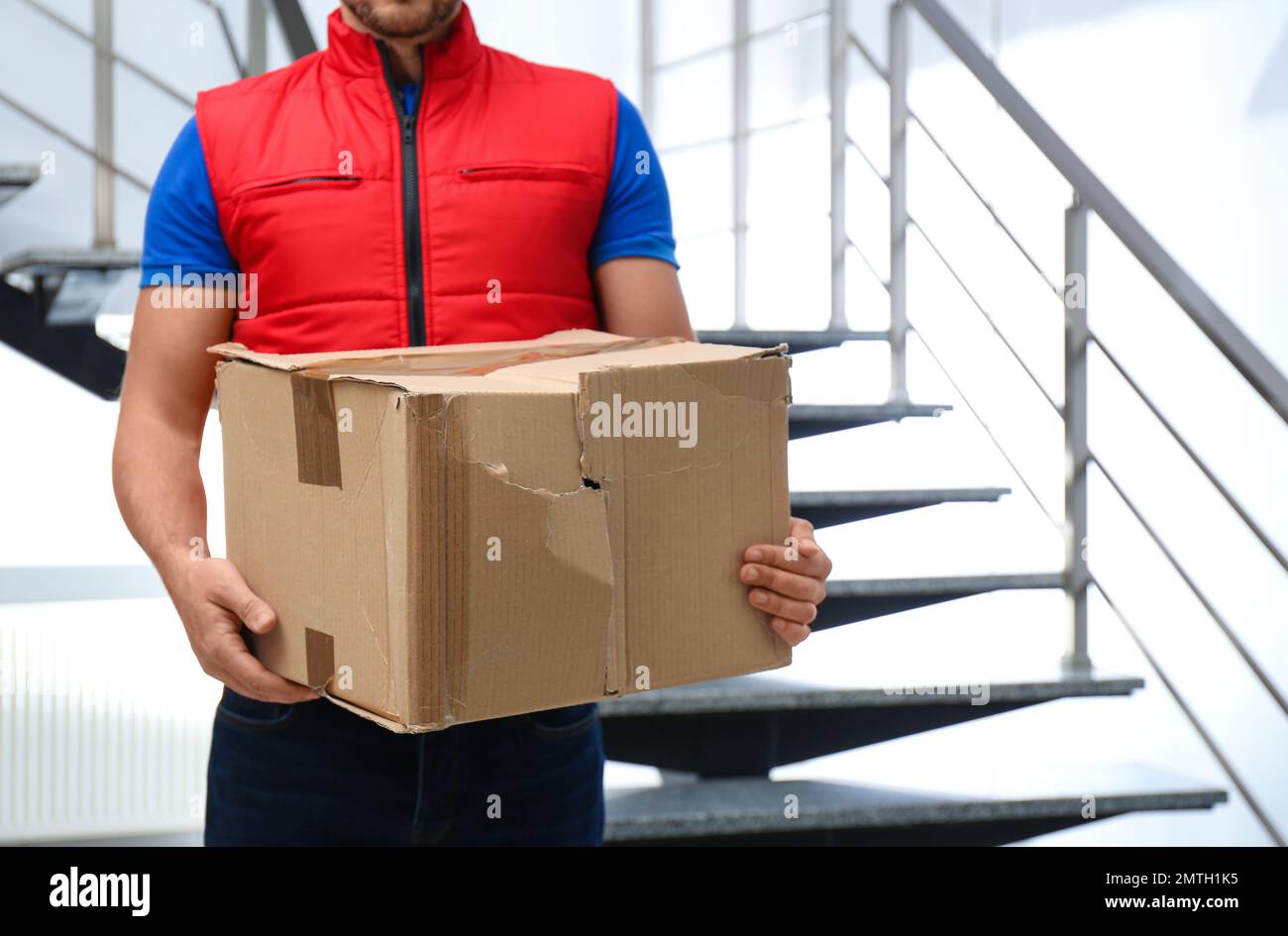 Courier with damaged cardboard box indoors, closeup. Poor quality ...