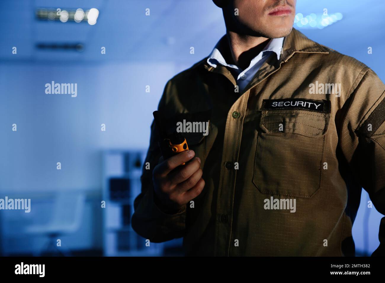 Professional security guard with portable radio set in dark room ...