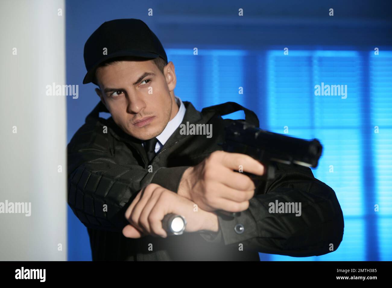 Professional security guard with flashlight and gun in dark room Stock ...