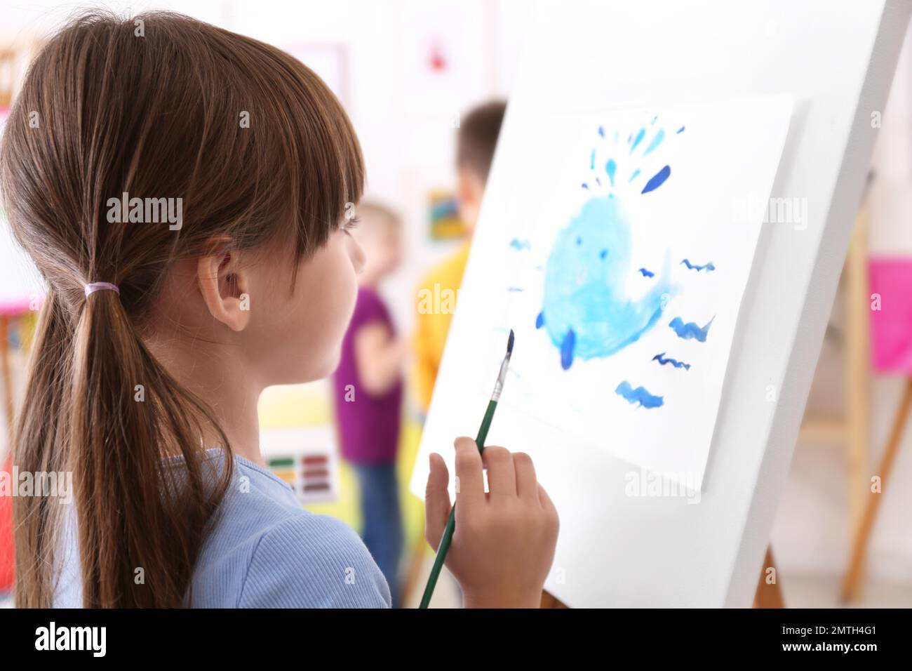 Cute little child painting during lesson in room Stock Photo - Alamy