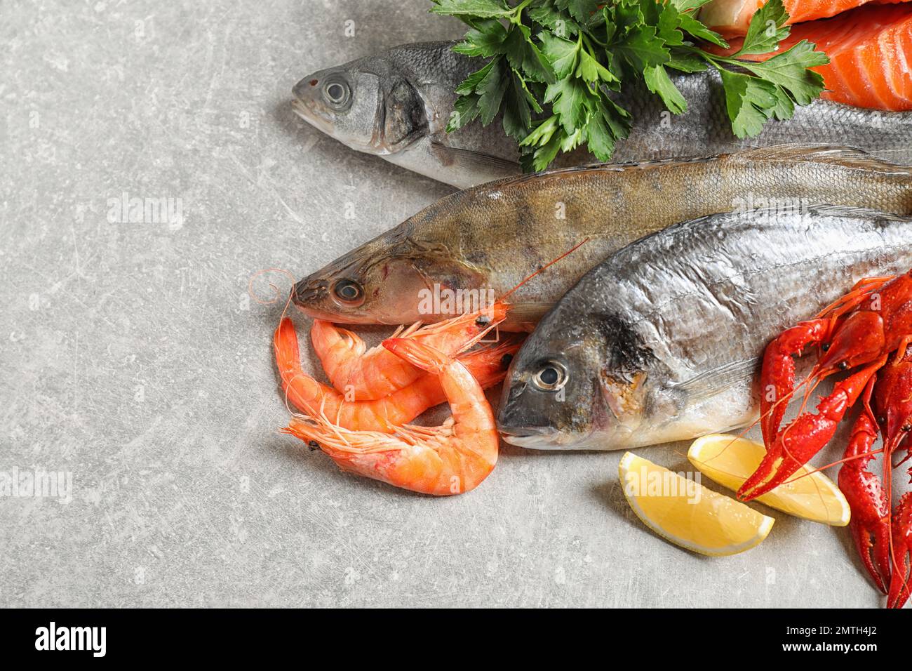 Fresh raw fish and different seafood on light grey table Stock Photo ...