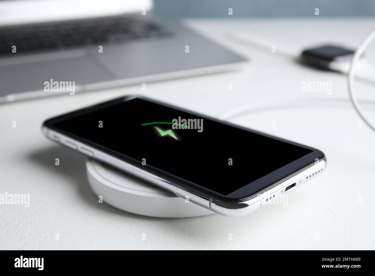 Mobile phone charging with wireless pad on white stone table, closeup ...