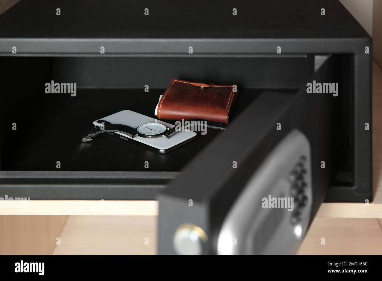 Open steel safe with wallet, watch and smartphone in wooden closet at ...