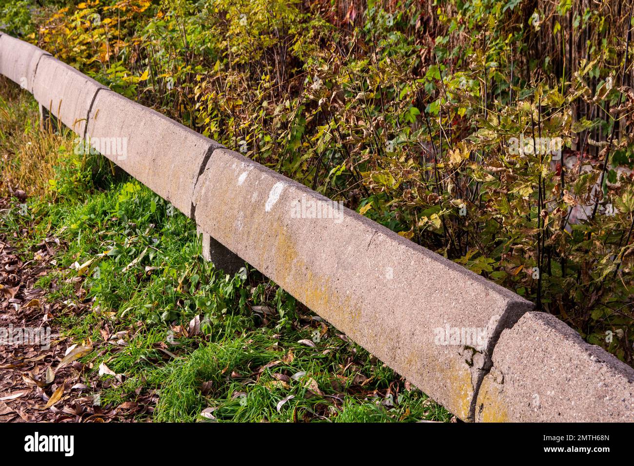 A concrete railing by a deserted and neglected road on a gloomy autumn ...