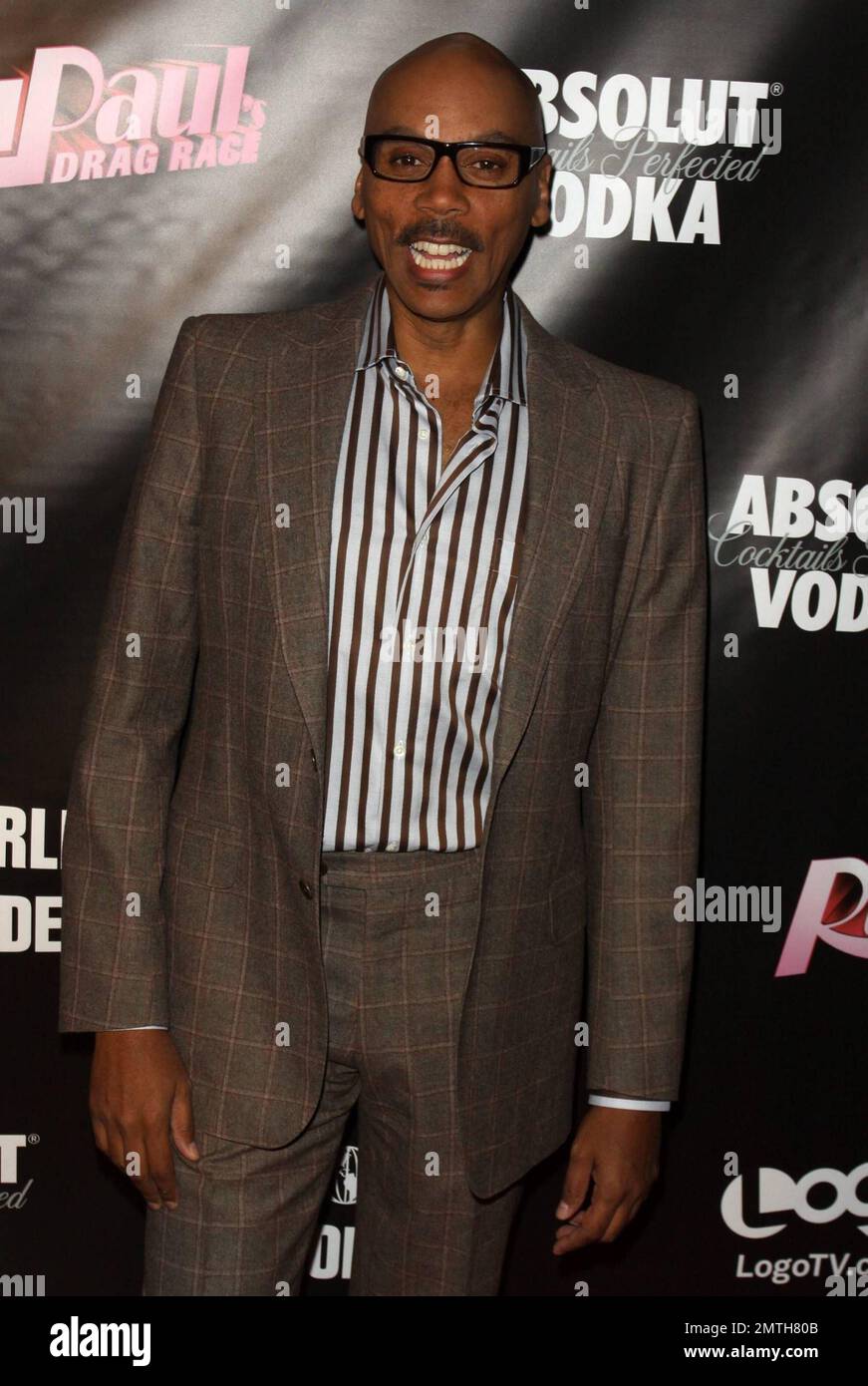 RuPaul looks sharp in a brown suit with striped shirt and glasses, a ...