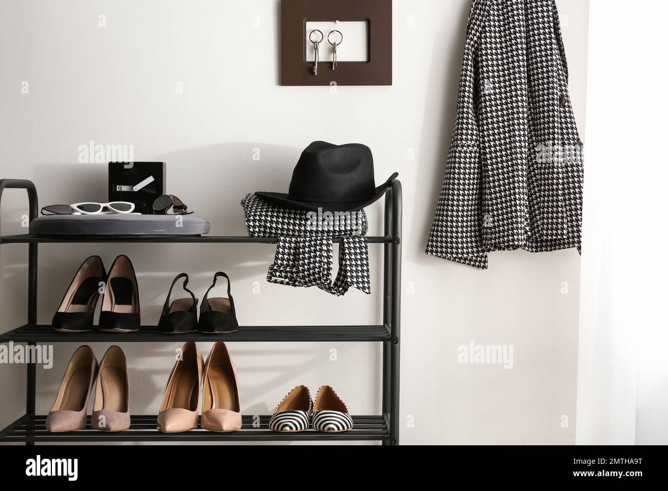 Black shelving unit with shoes and different accessories near white ...
