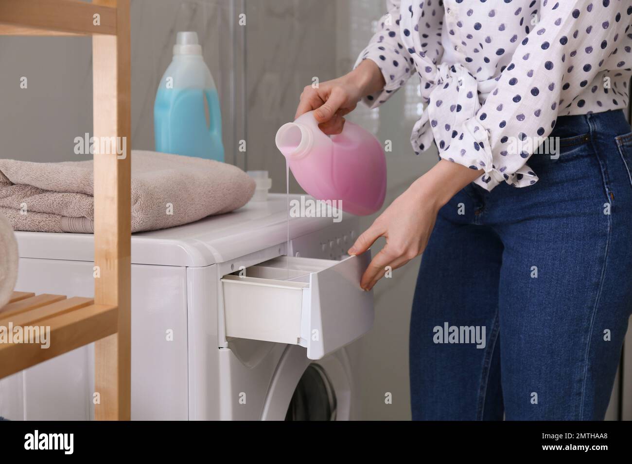 Woman pouring detergent into washing machine drawer in bathroom ...