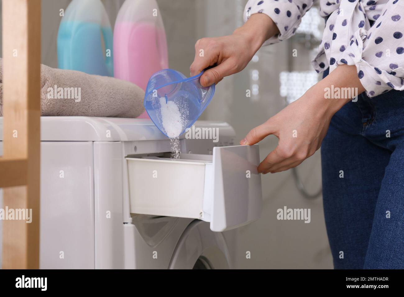 Woman pouring laundry detergent into washing machine drawer in bathroom ...