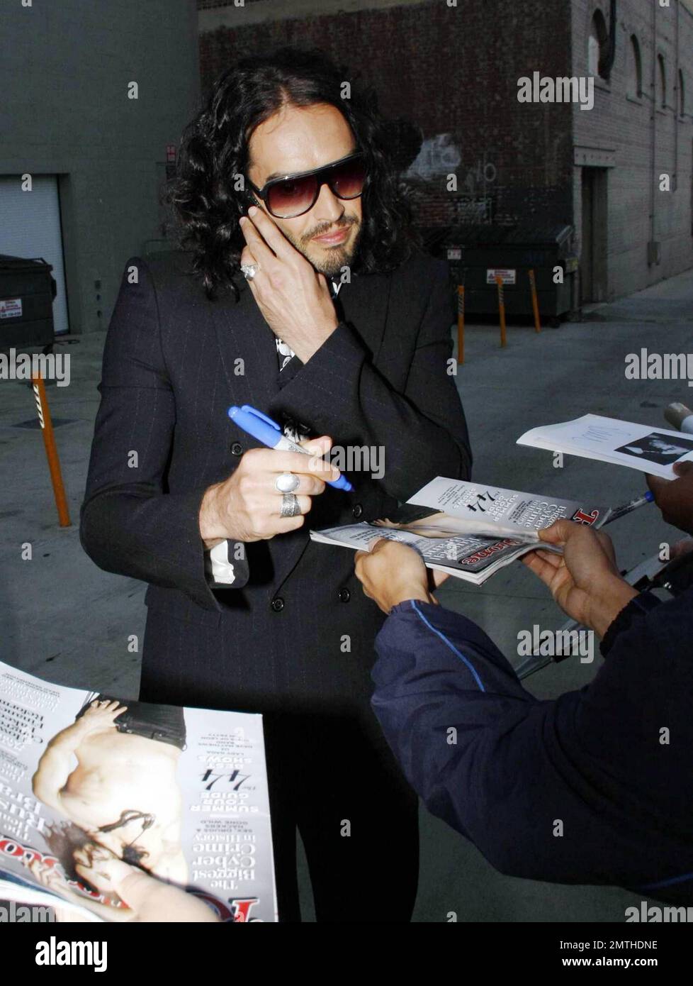 Russell Brand multi-tasks as he arrives for an appearance on the "Jimmy ...