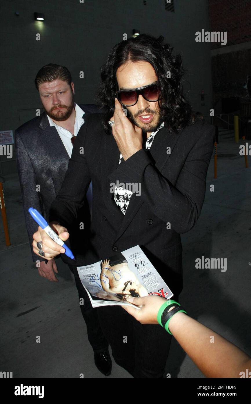 Russell Brand multi-tasks as he arrives for an appearance on the "Jimmy ...