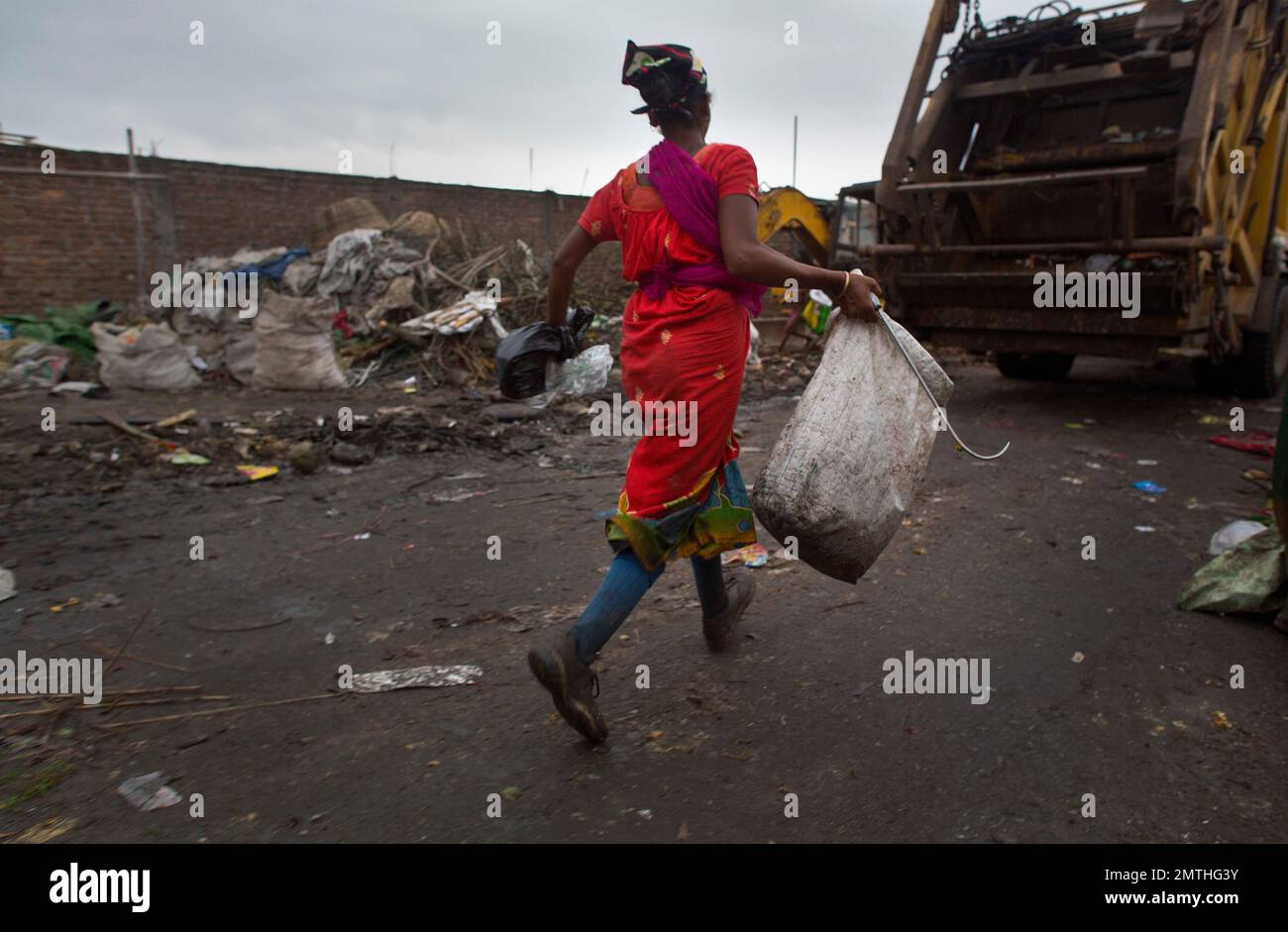 An Indian ragpicker woman runs behind a dumper truck that arrives to ...