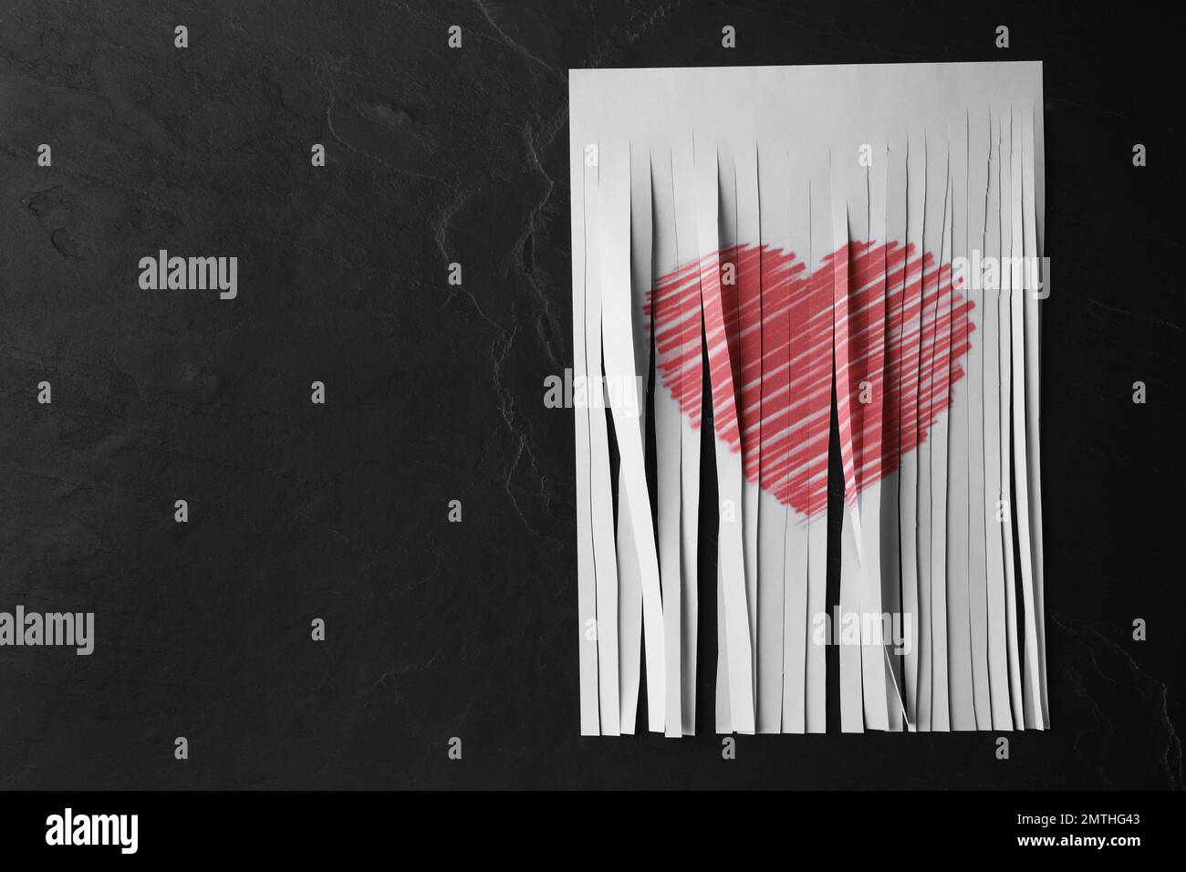 Top view of cut paper with heart drawing on black stone background ...