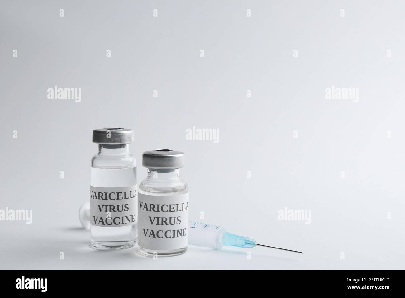 Chickenpox vaccine and syringe on light grey background, space for text ...