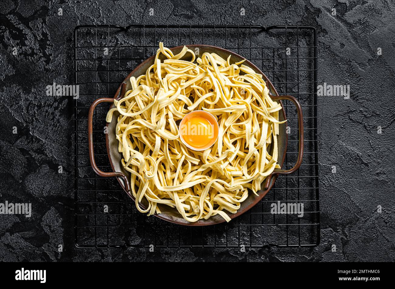 Dry spaetzle egg noodle in a steel tray. Black background. Top view ...