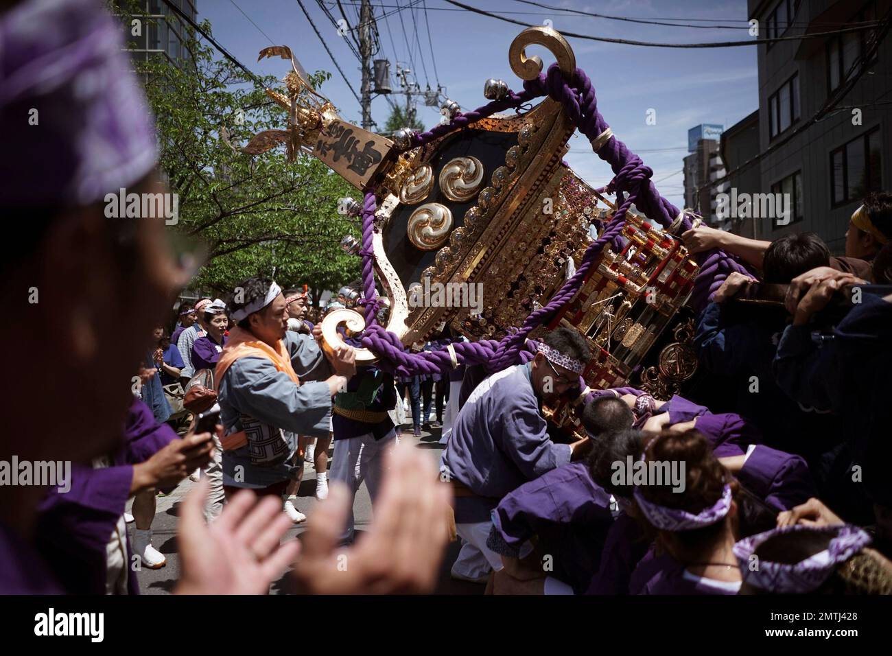 Participants clad in traditional "happi" coats swing the "mikoshi," or portable shrine to left ...