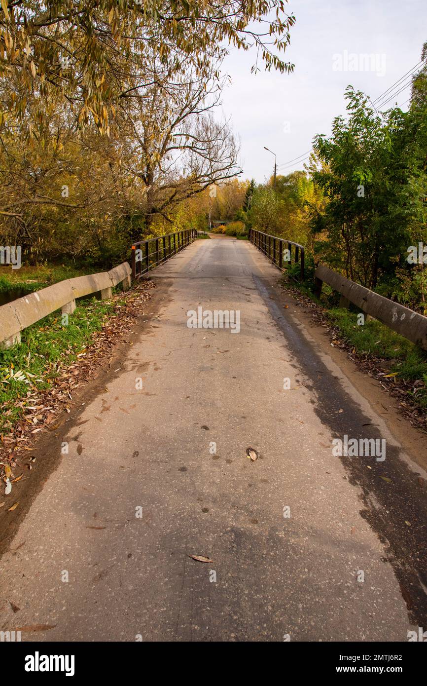 A concrete railing by a deserted and neglected road on a gloomy autumn ...
