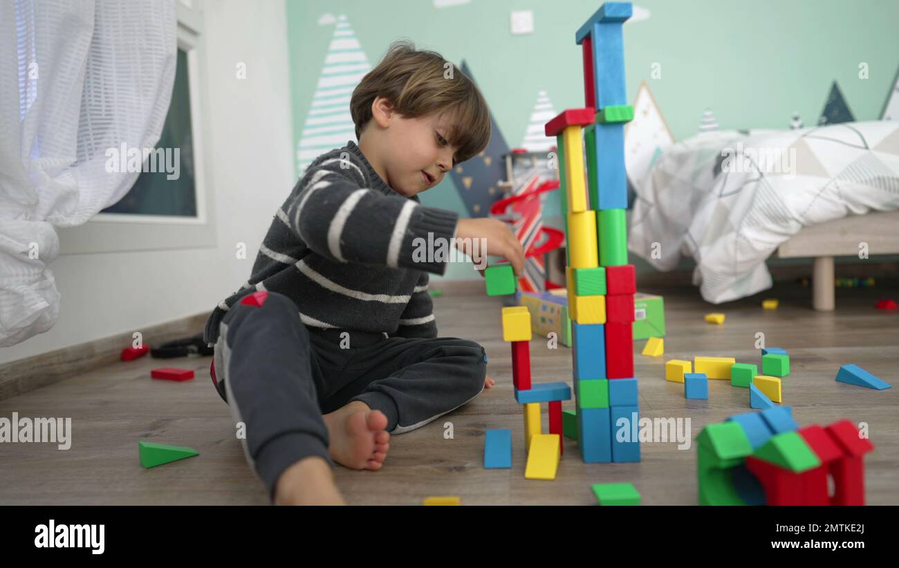 Child plays with building blocks on floor. Lifestyle shot of kid ...