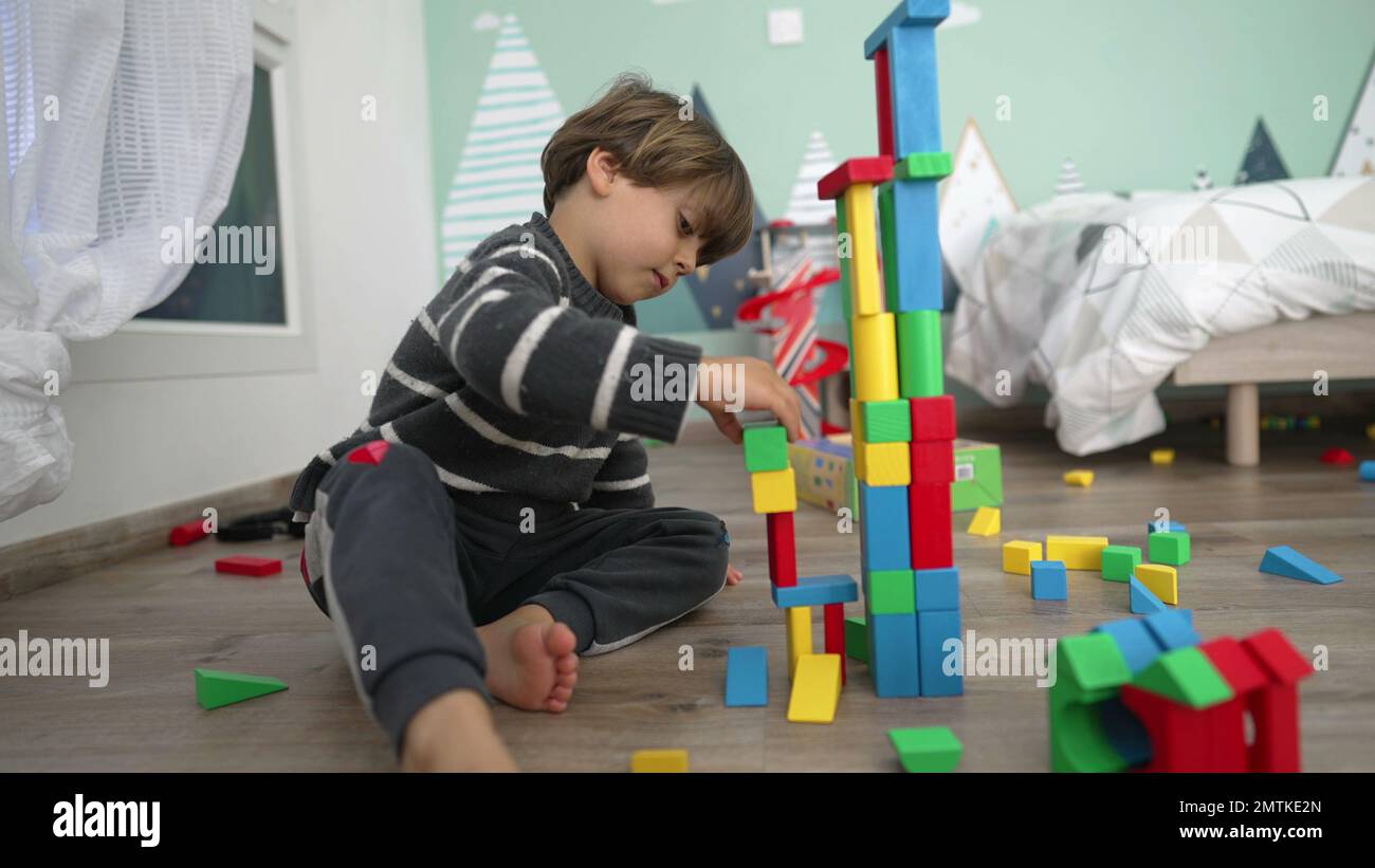 Child playing with toy blocks on bedroom floor. Creative kid sitting on ...