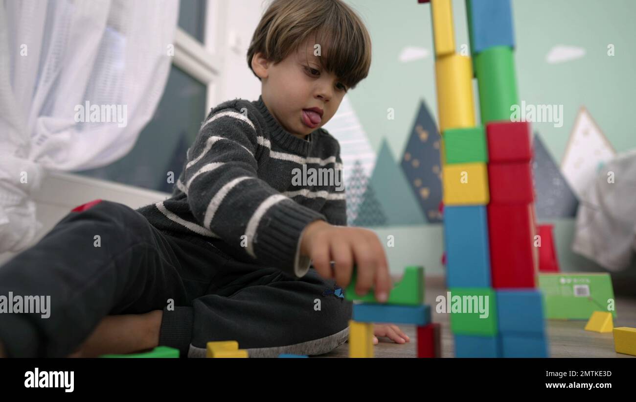 Child playing with toy blocks on bedroom floor. Creative kid sitting on ...