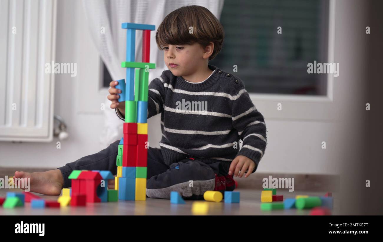 Child building tower with colorful blocks. One small boy playing in ...