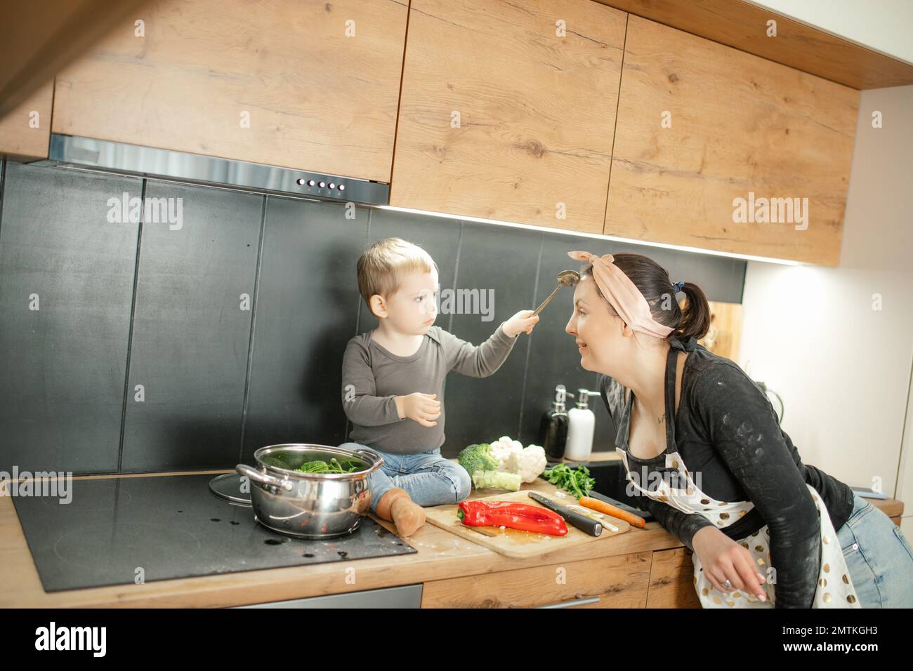 Mother with little child cook dinner side view. Baby son sitting on ...