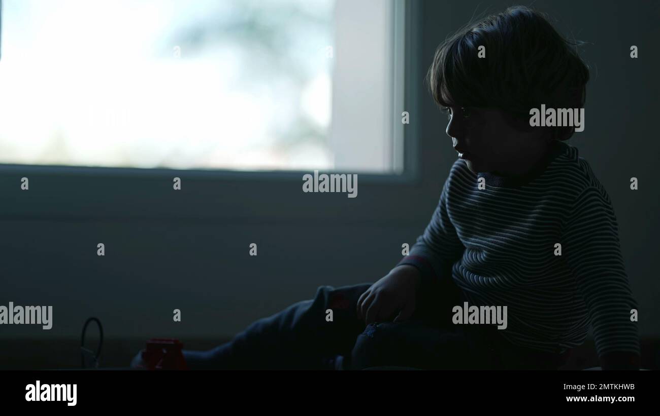 One depressed child sitting in the dark. Lonely little boy on floor ...