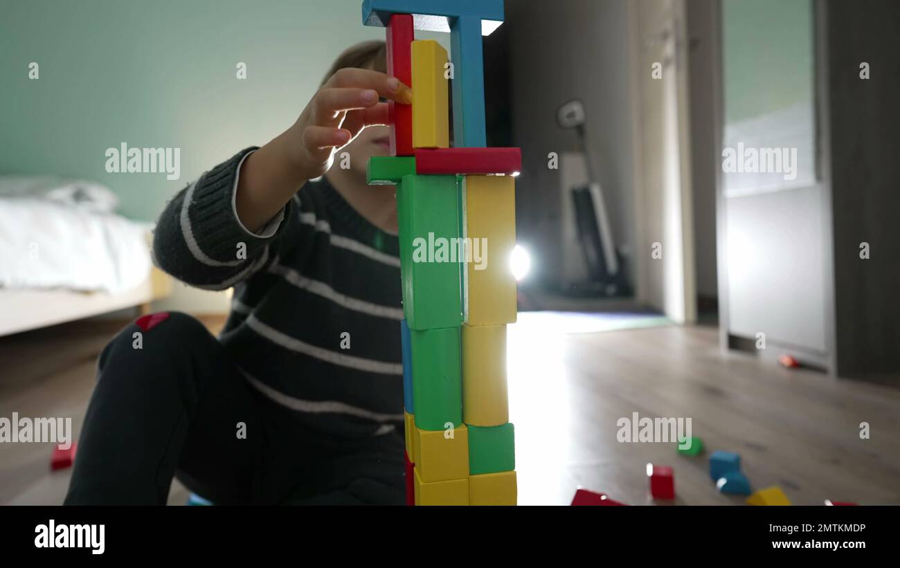 Small boy plays with building blocks. Child dropping block accidentally ...