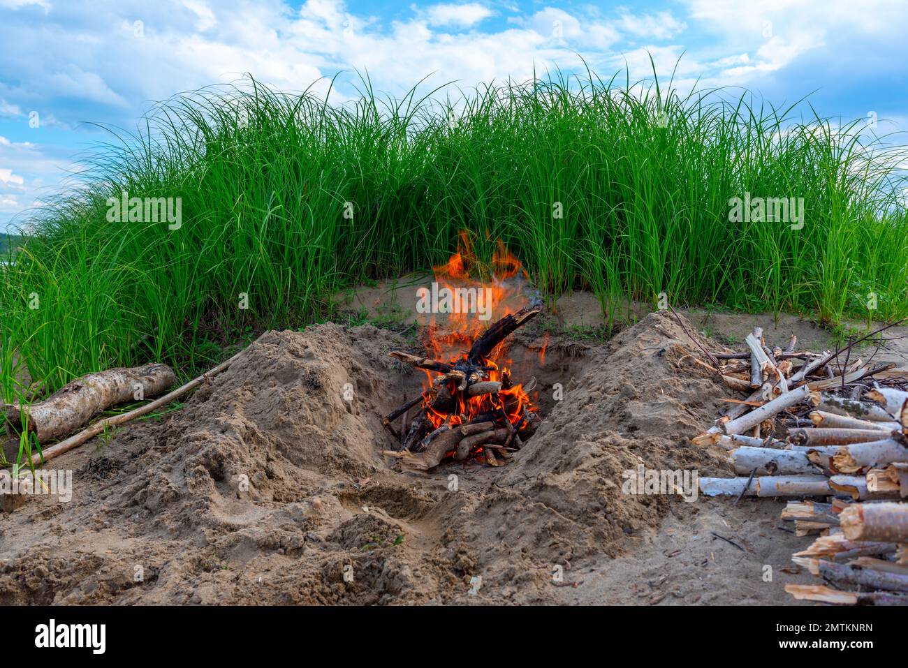 The campfire on the beach burns on a bright day in the sand next to ...