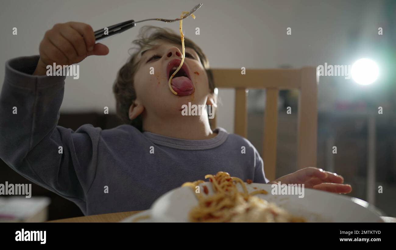 Small boy eating pasta at home for dinner. Child plays with spaghetti ...