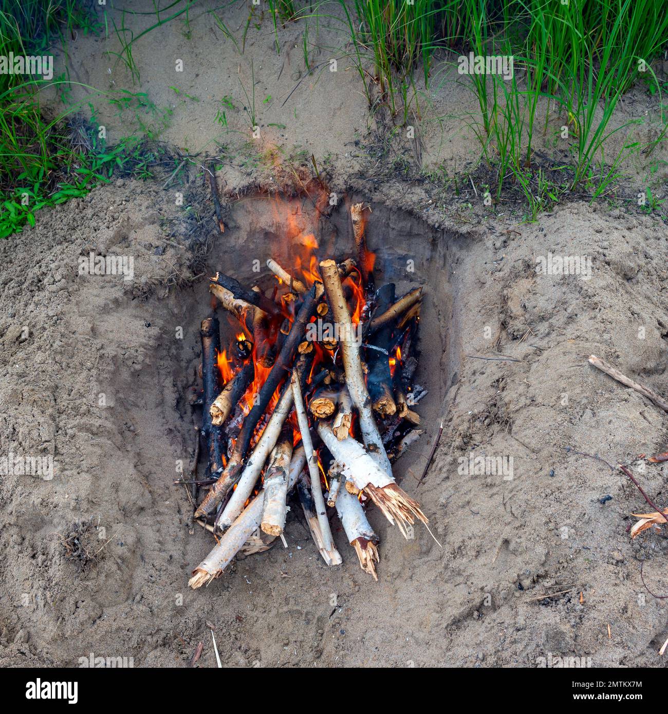 A photo of a fire made of birch branches taken from above in the sand ...