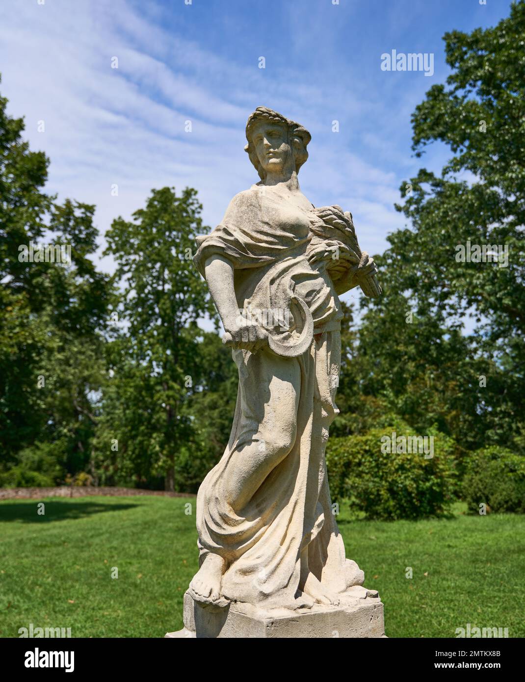 A vertical of a statue of a Greek goddess captured in a beautiful green ...
