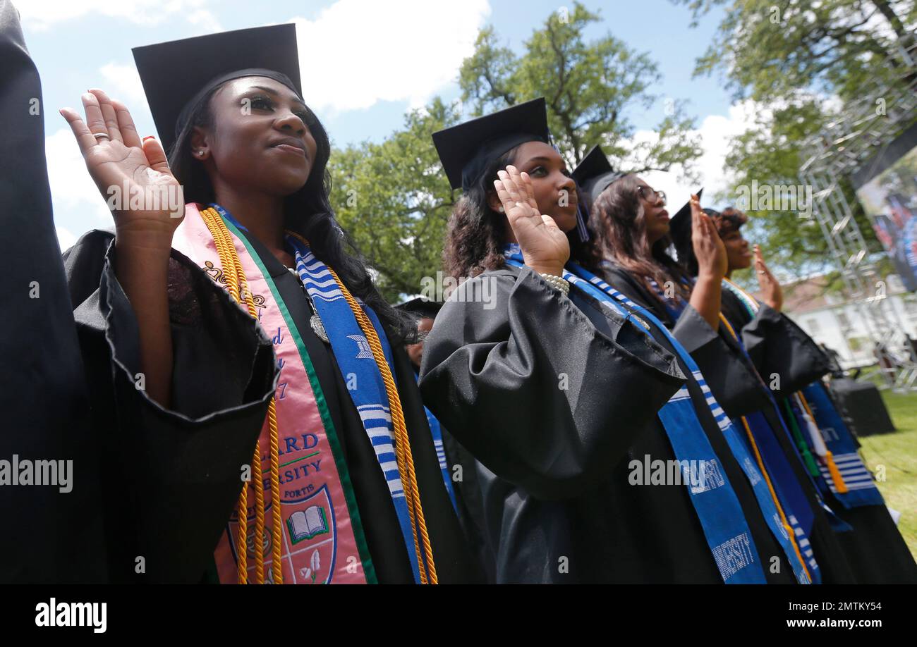 In this Saturday, May 13, 2017 photo, graduates hold up their hands ...