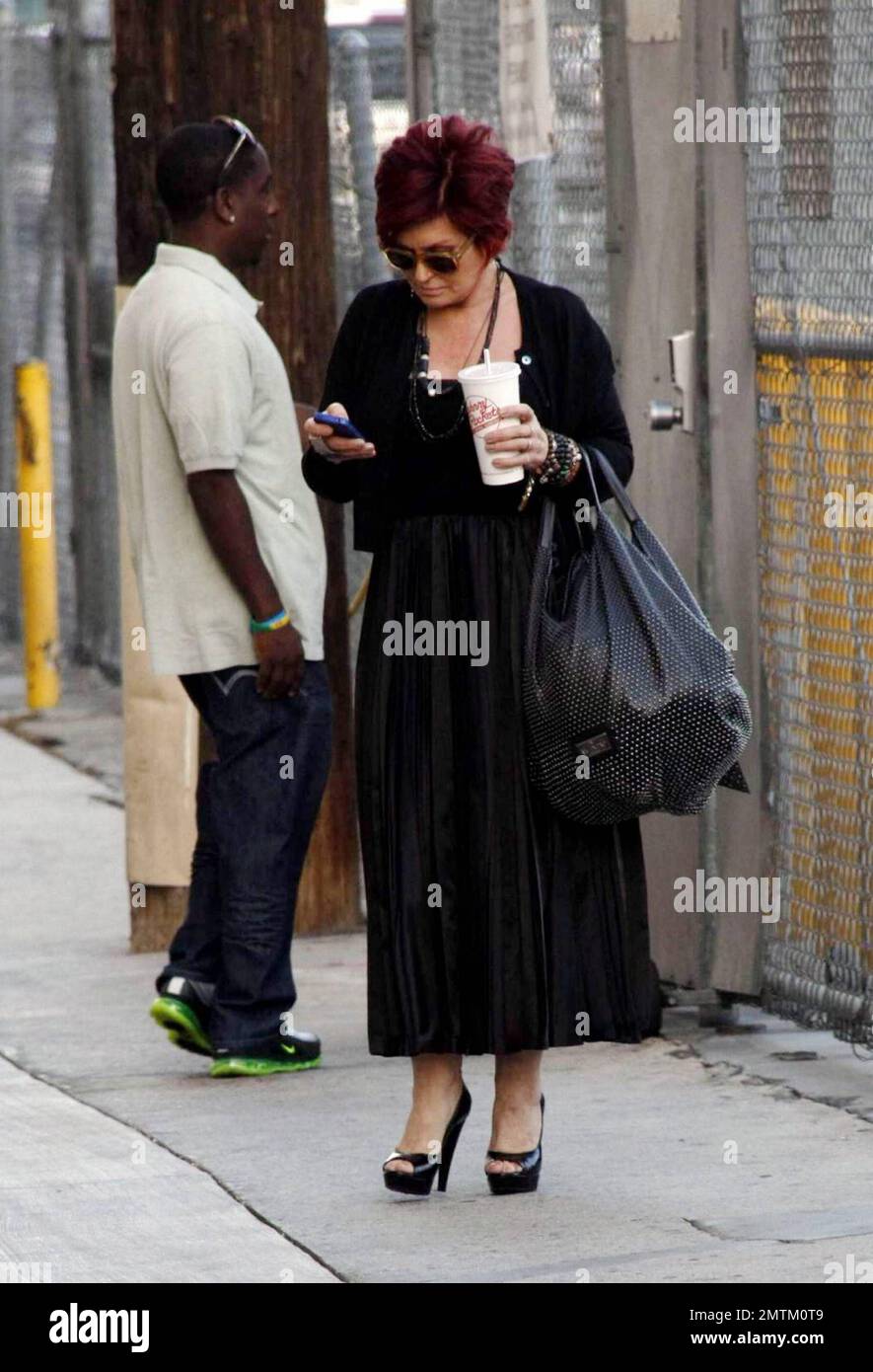 Sharon Osbourne waves to the cameras while checking her messages after ...