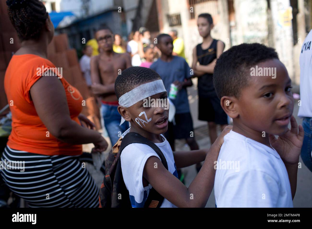 A student has his face painted with the Portuguese word "Peace" during ...