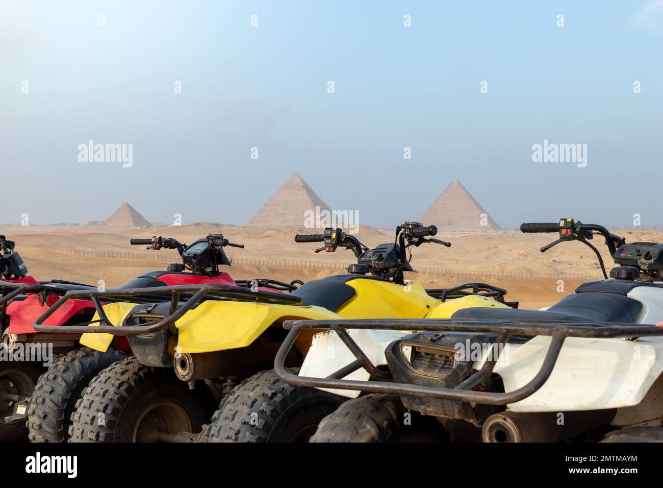 Colorful parked quad bikes ATV safari in desert with pyramids in ...