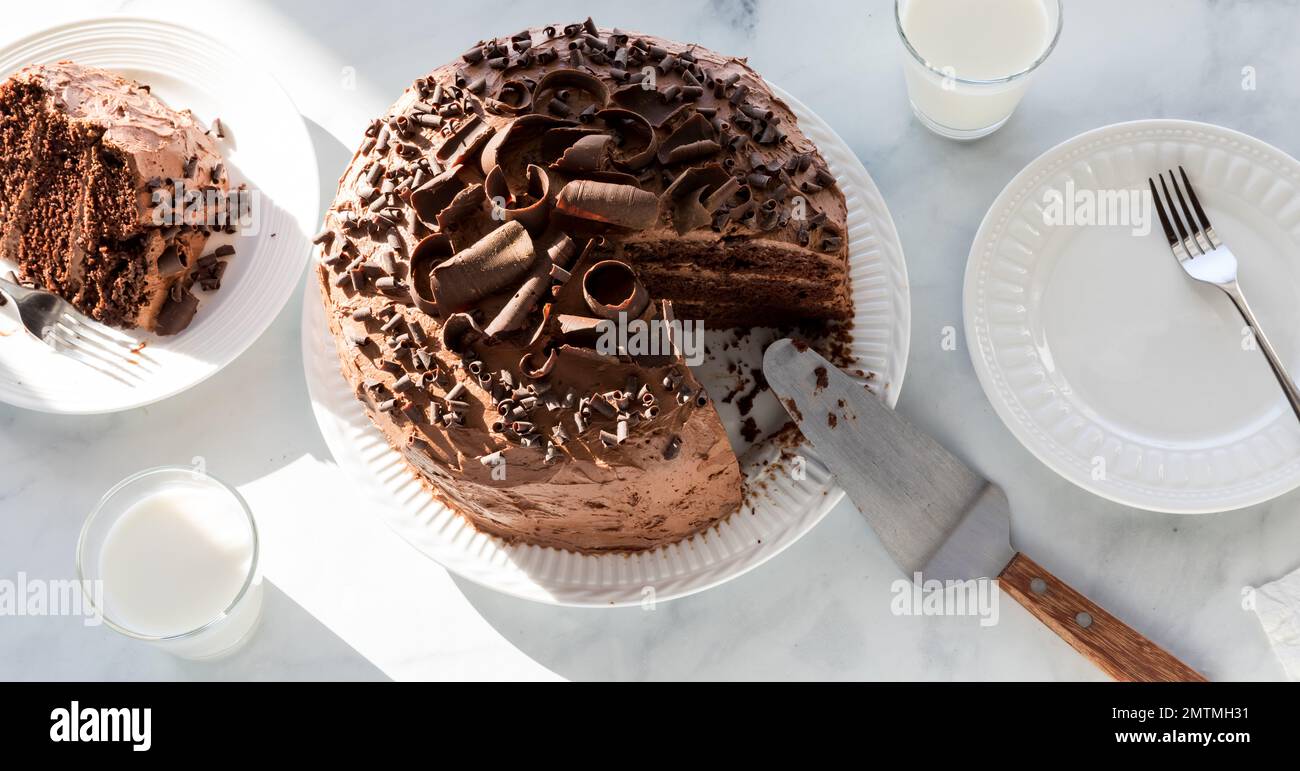 A chocolate cake decorated with chocolate curls with one slice to the ...