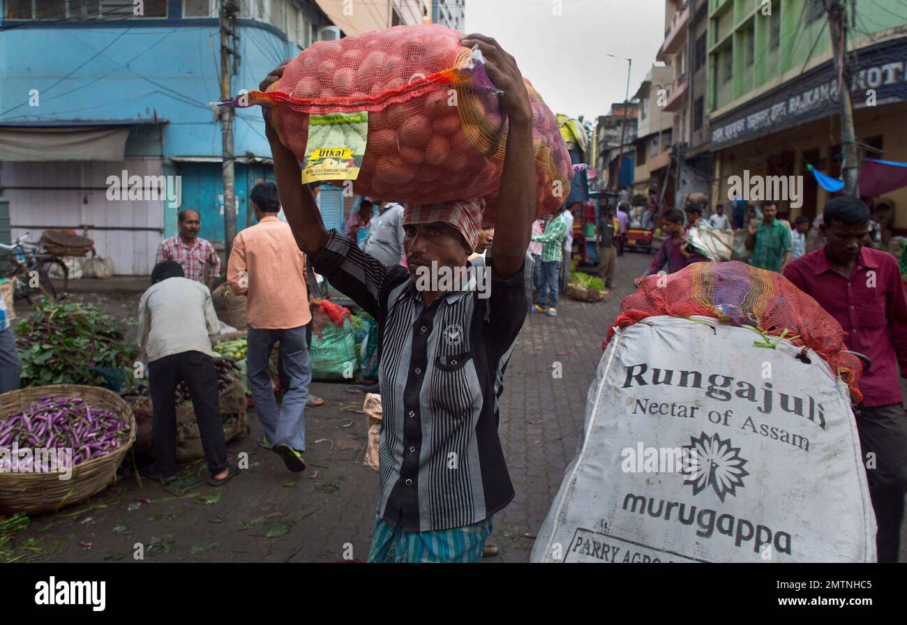 An Indian laborer carries a potato sack on his head at a vegetable ...